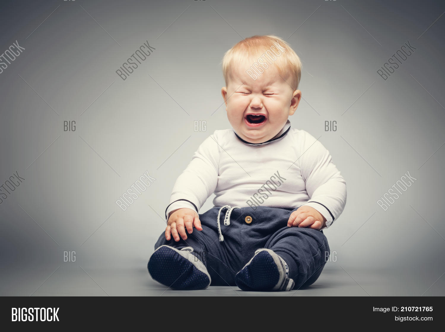 Little baby boy sitting on the ground with crying face expression ...