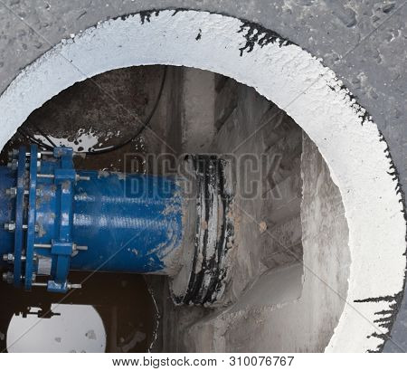 Open Manhole In The Concrete Block. Blue Pipe In The Manhole. Coupling ...