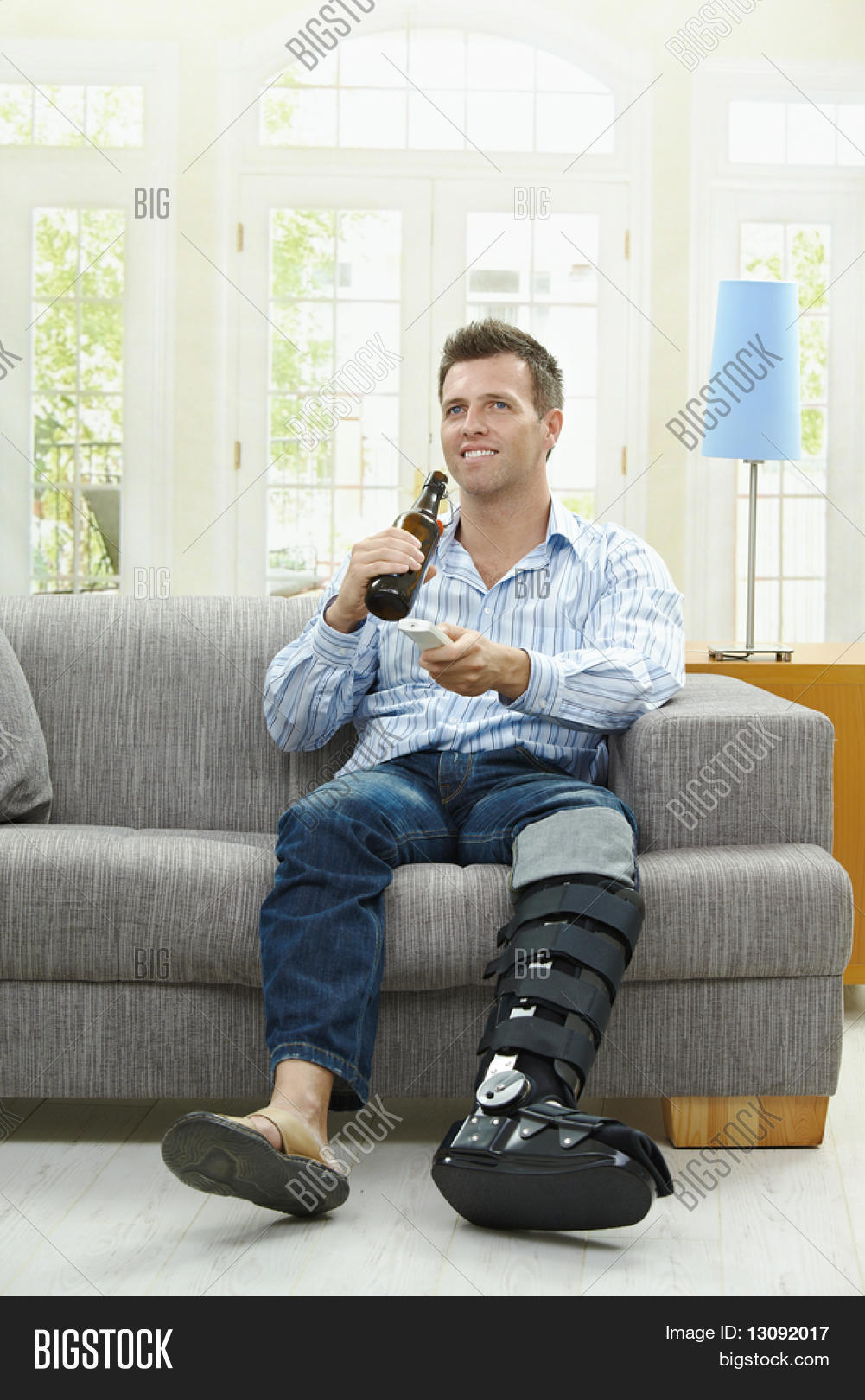 Man watching TV at home, sitting on couch, holding remote control in ...