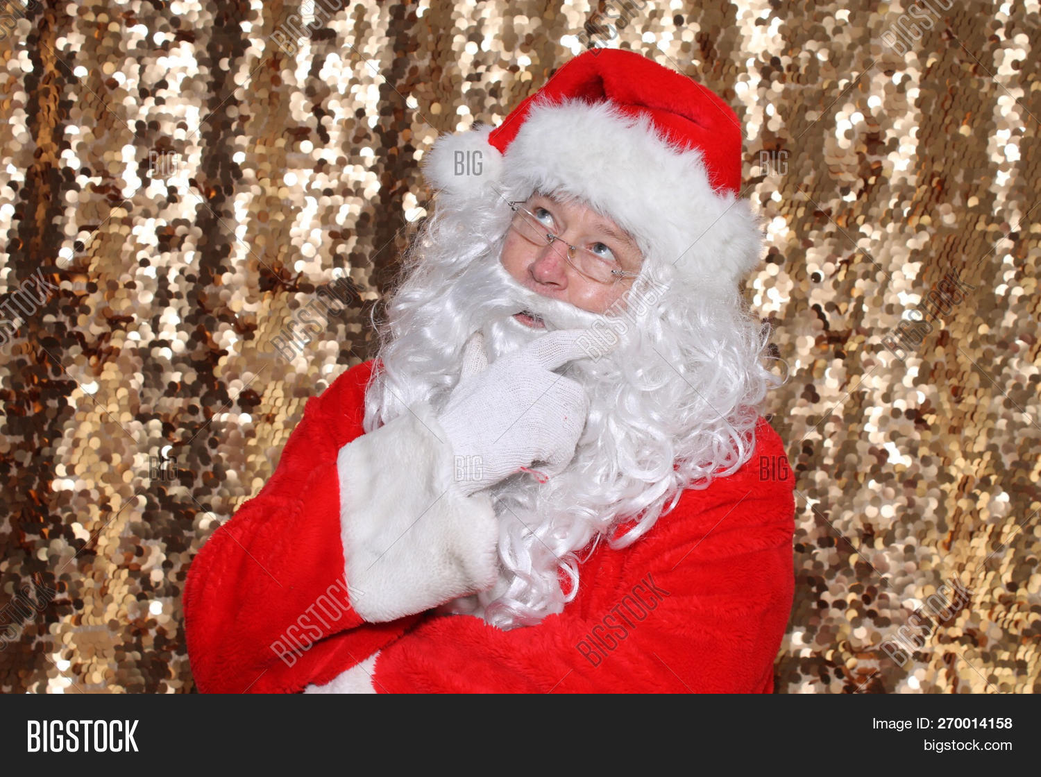 Santa Claus. Santa Claus holds his fingers to his face and he is deep ...