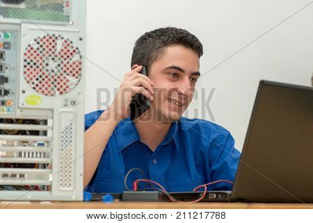 a young man technician working on broken computer and call the customer ...