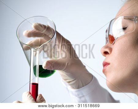A Female Laboratory Employee Conducts An Experiment With Liquids Of Red ...