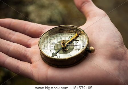 Closeup of hand holding old magnetic golden compass and showing ...