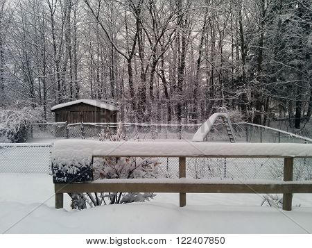 Winter deck overlooking inground pool area and pool shed in winter ...