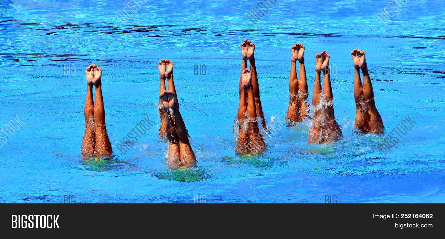 Synchronized Swimmers Point Up Out Of The Water In Action. Synchronized ...