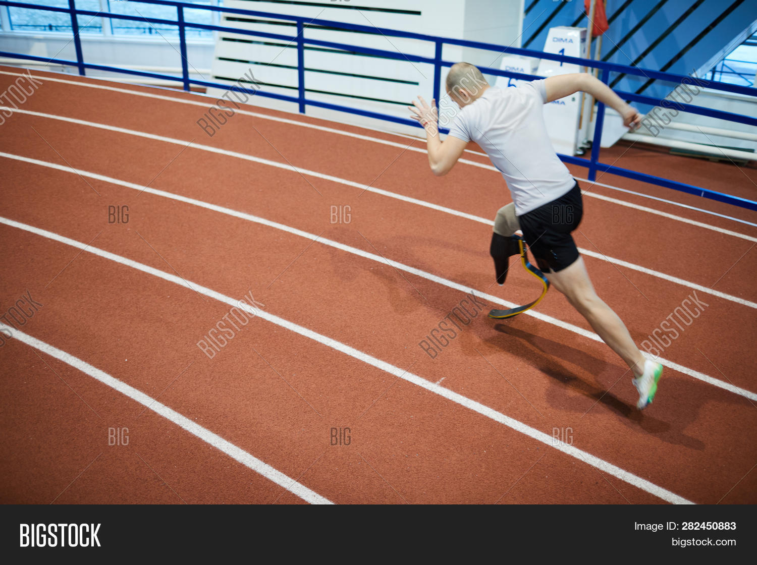 Active runner with handicapped leg moving fast on track line at stadium ...