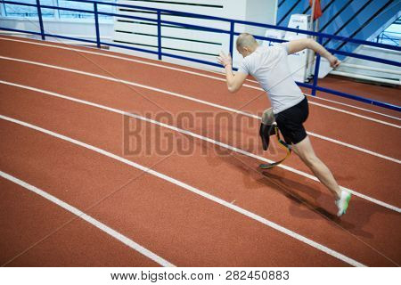 Active runner with handicapped leg moving fast on track line at stadium ...