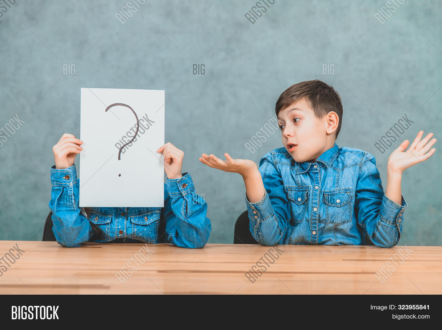Schoolchildren Sitting At The Desk. Girl Is Hiding Behind The Sheet Of ...