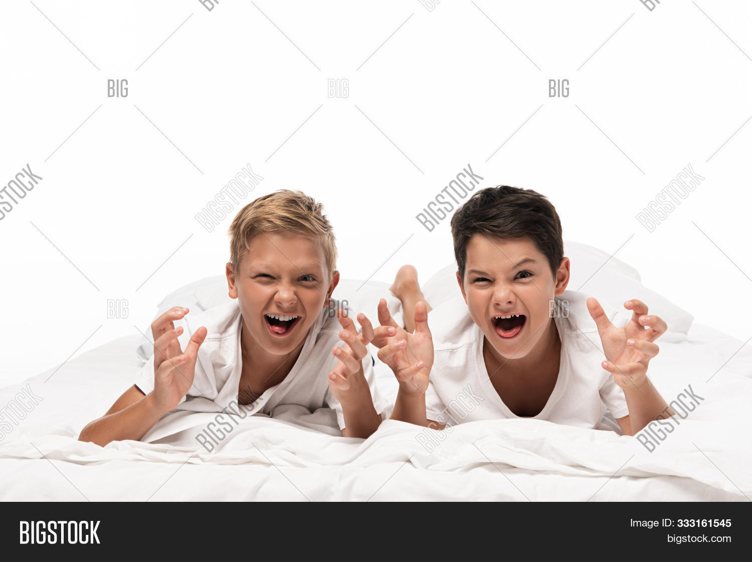 Two Brothers Grimacing And Showing Frightening Gestures While Lying On ...