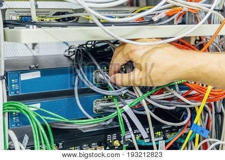 Engineer connecting network cable to switch of fiber optic hub for ...