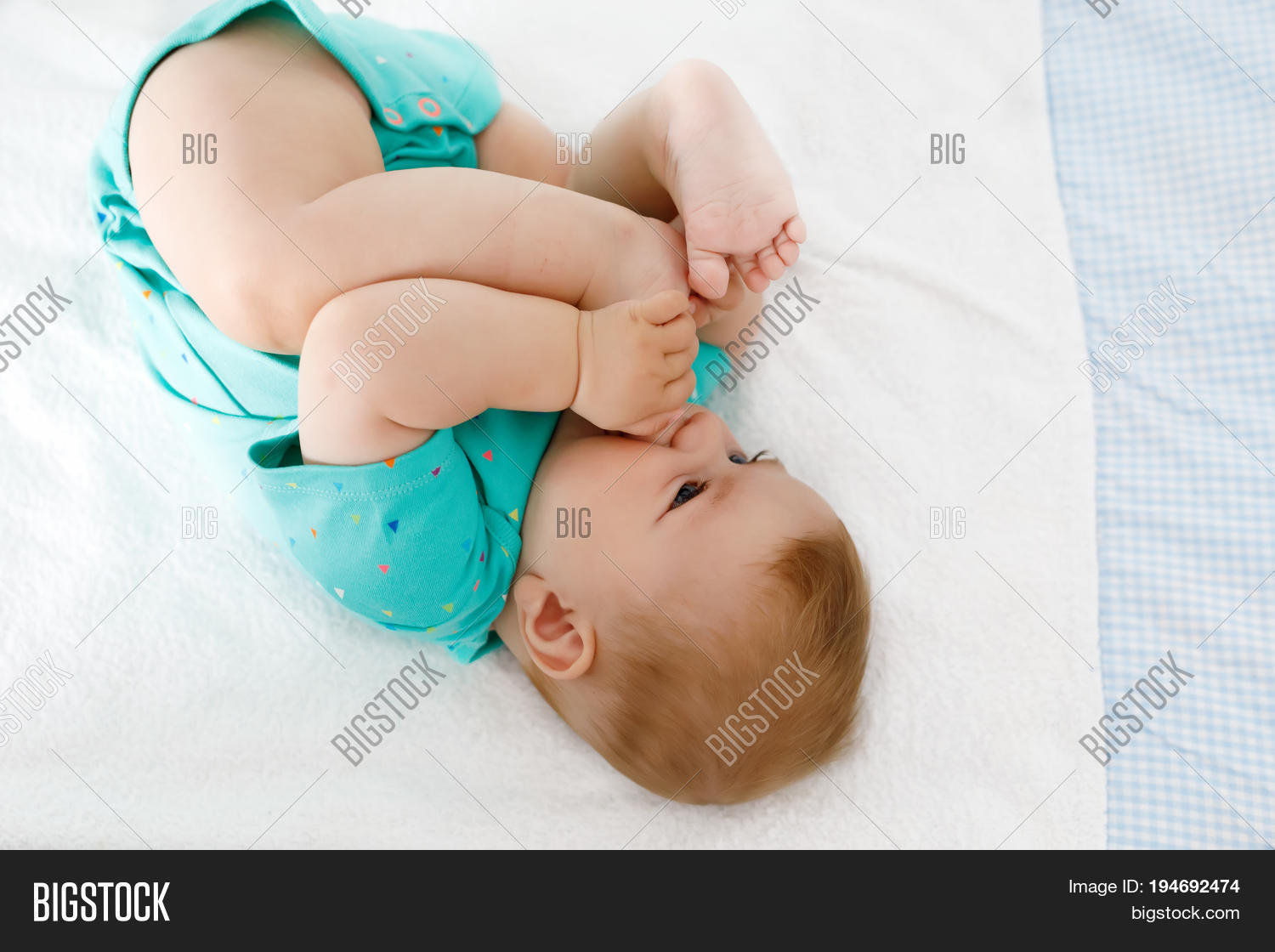 Cute baby taking feet in mouth image & stock photo. 194692474