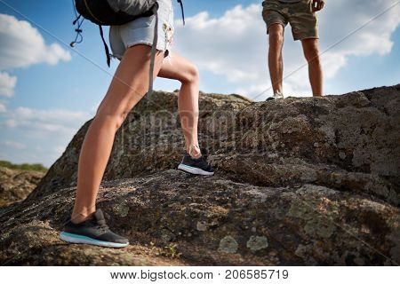 Sport legs. Woman hiker climbing rock on mountain peak cliff, her man ...