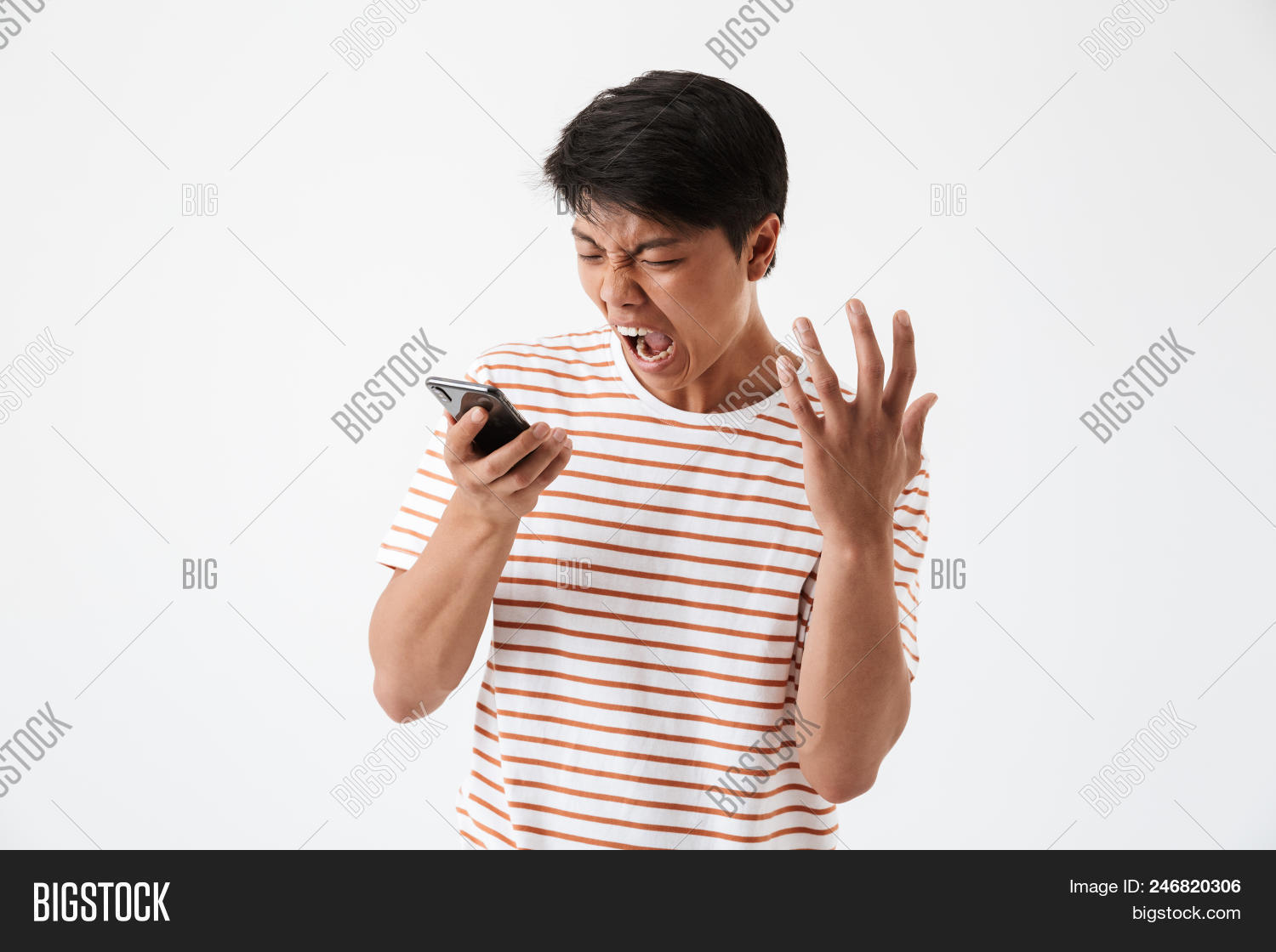 Portrait of an angry young asian man yelling at mobile phone isolated ...