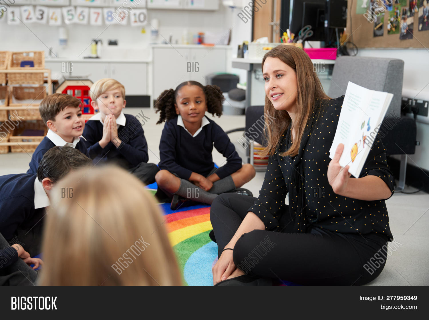 Primary school children sitting on the floor in the classroom with ...