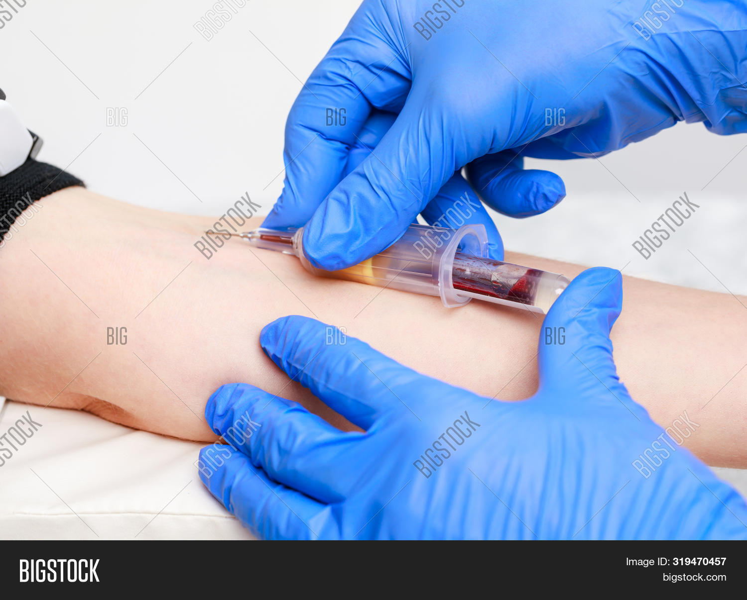 Close-up shot of doctor or nurse taking a blood sample from arm vein ...