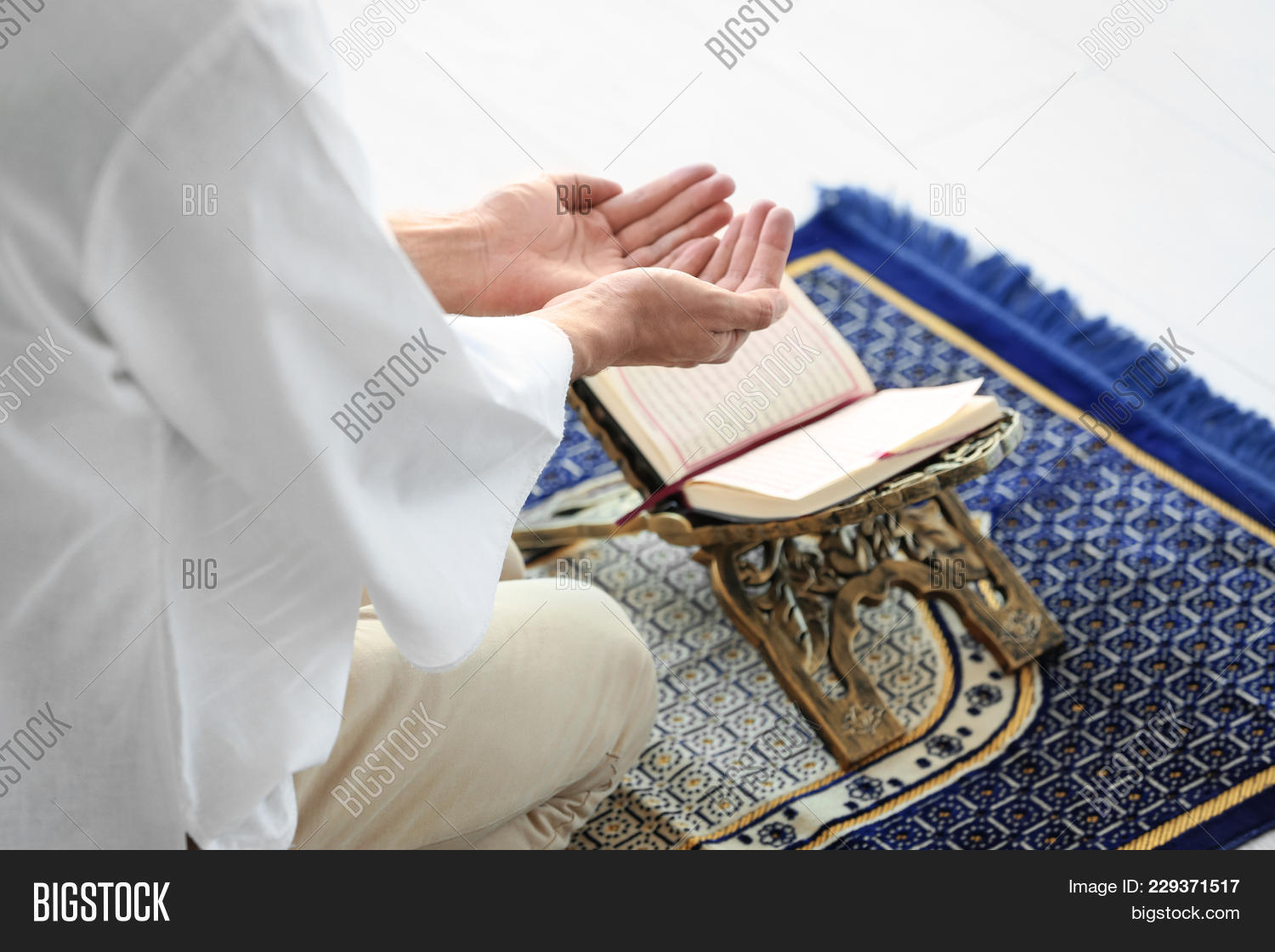 Young Muslim man praying over Koran on floor image & stock photo. 229371517
